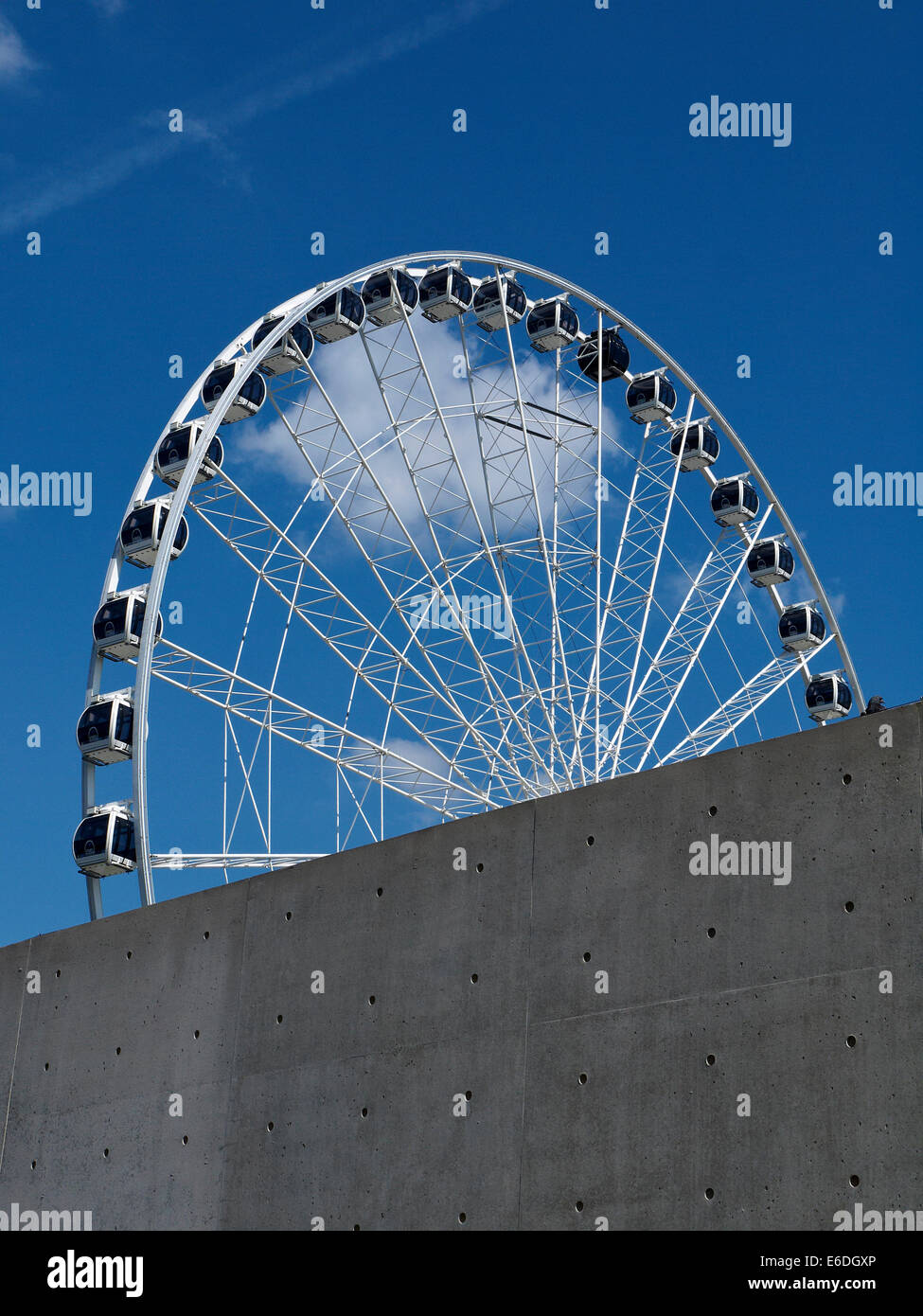 Ferris wheel behind concrete wall at Piccadilly gardens in Manchester ...