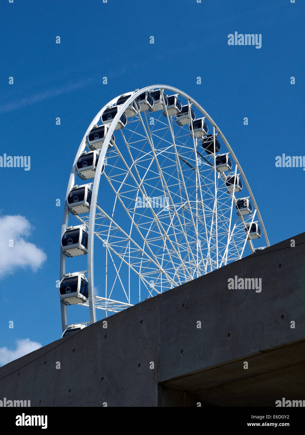 Ferris wheel behind concrete wall at Piccadilly gardens in Manchester ...