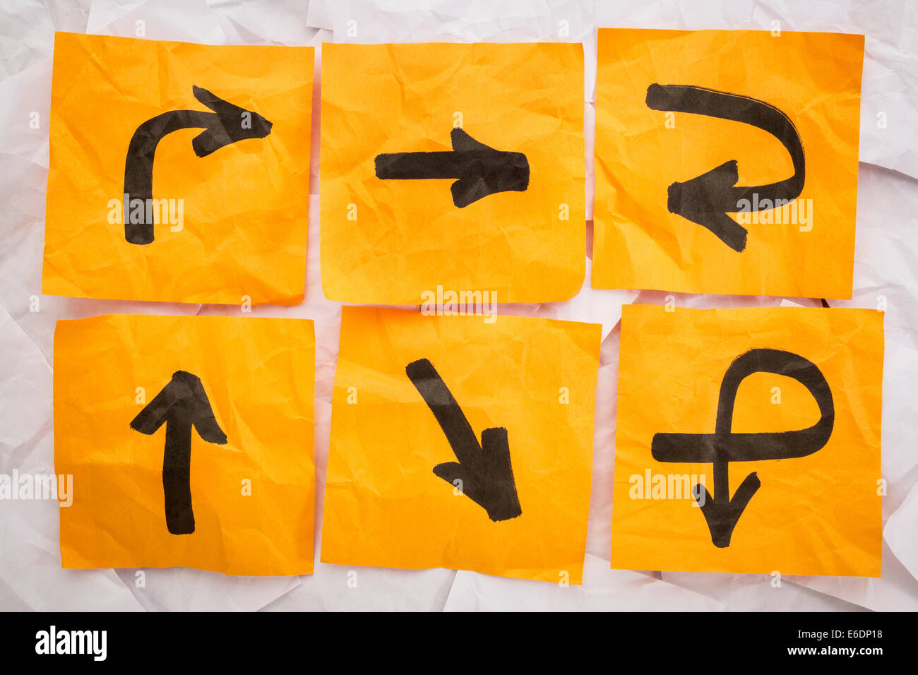 confusing directions concept - a variety of arrows on crumpled, orange ...