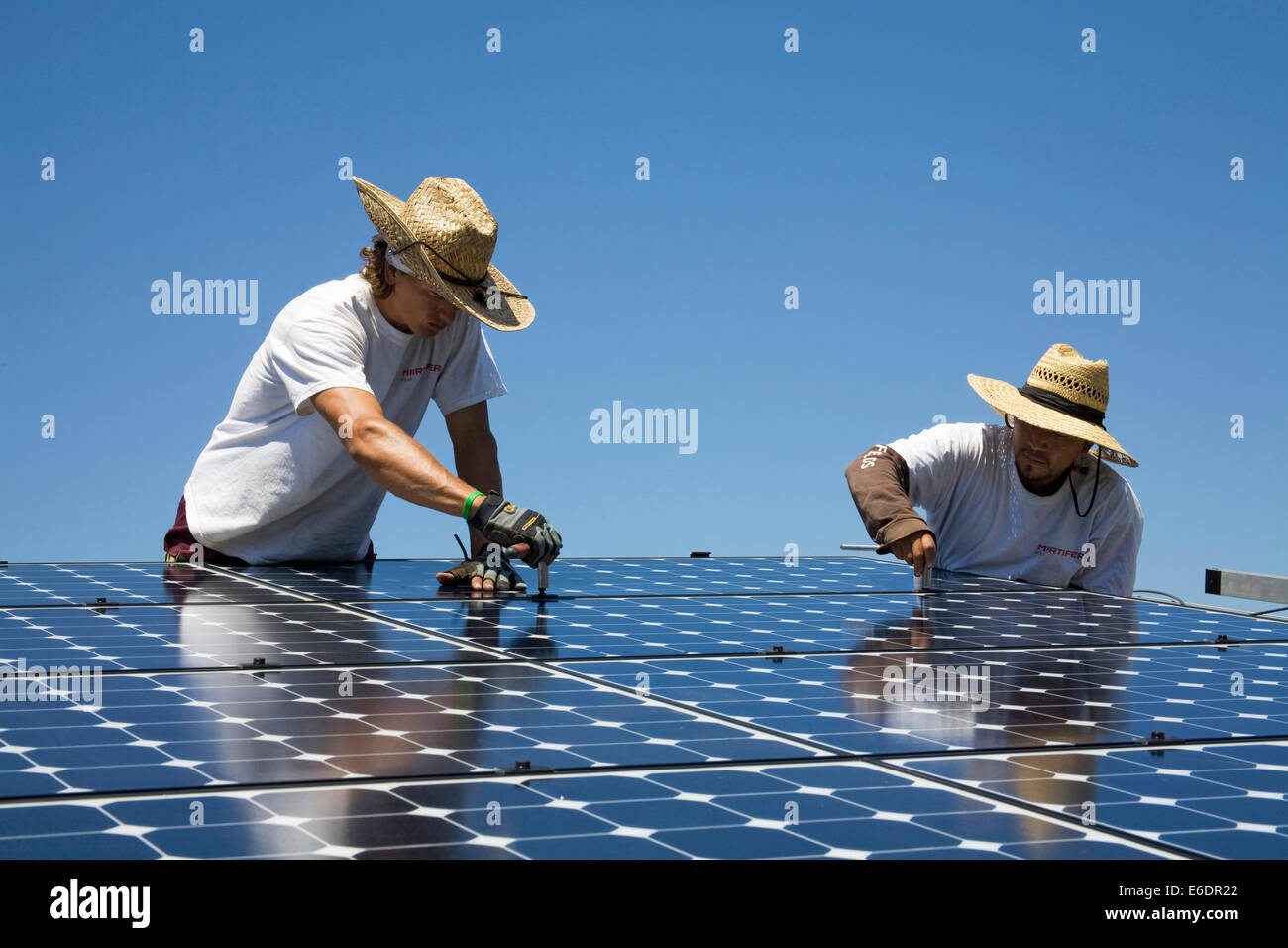 Green workers install a residential grid-tied solar array on a hillside ...