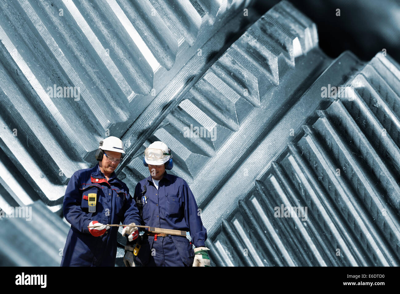 two engineers, workers with a giant cog and gears machinery in the ...