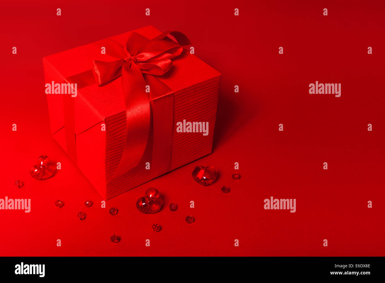Cute red box with bow and glass shiny hearts on the red background with ...