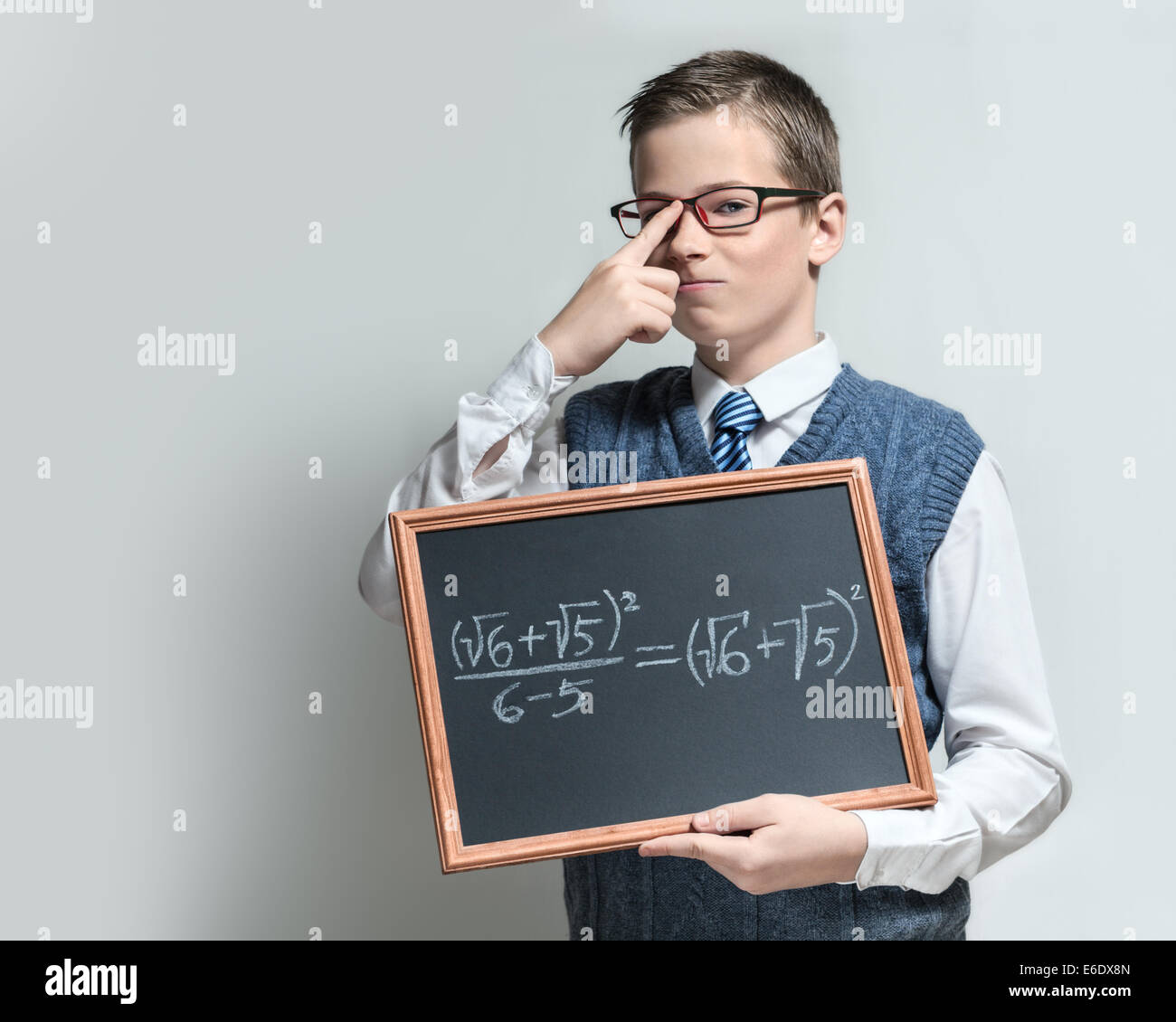 The smart schoolboy teenager in a glasses shows the chalkboard with the ...