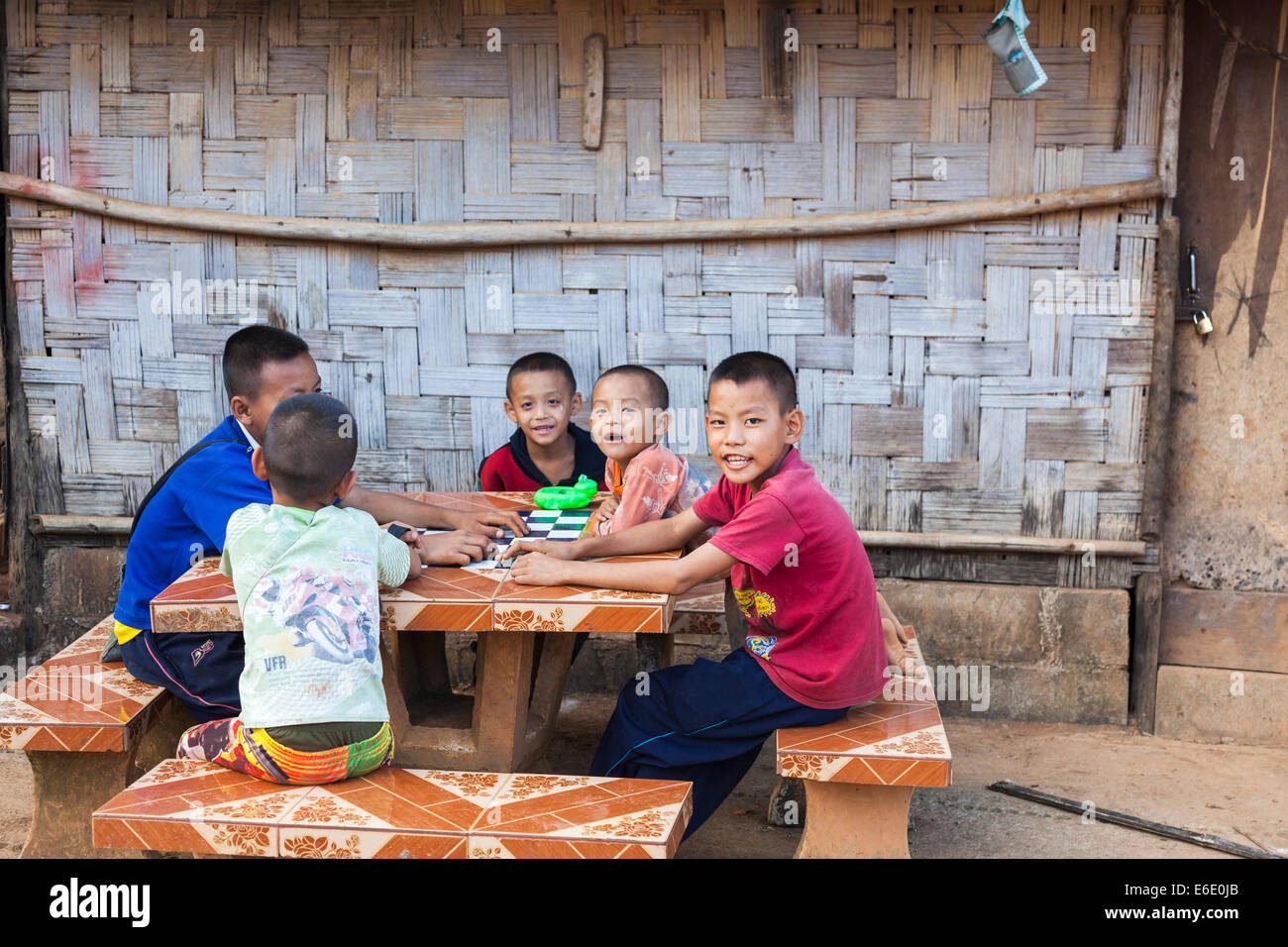 A group of happy children sat at a table in a Lahu village playing ...