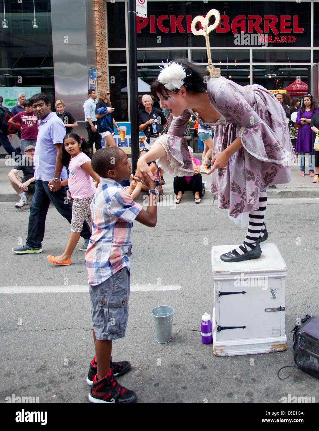 Toronto, Canada. 21st Aug, 2014. A busker interacts with a boy during ...