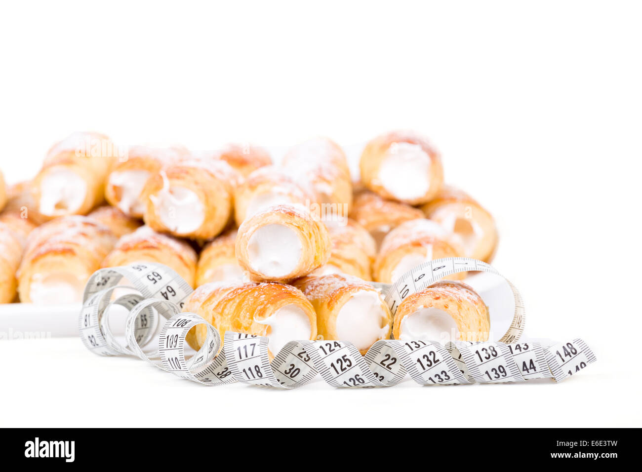 concept of slimming, cakes with measuring tape on white background ...