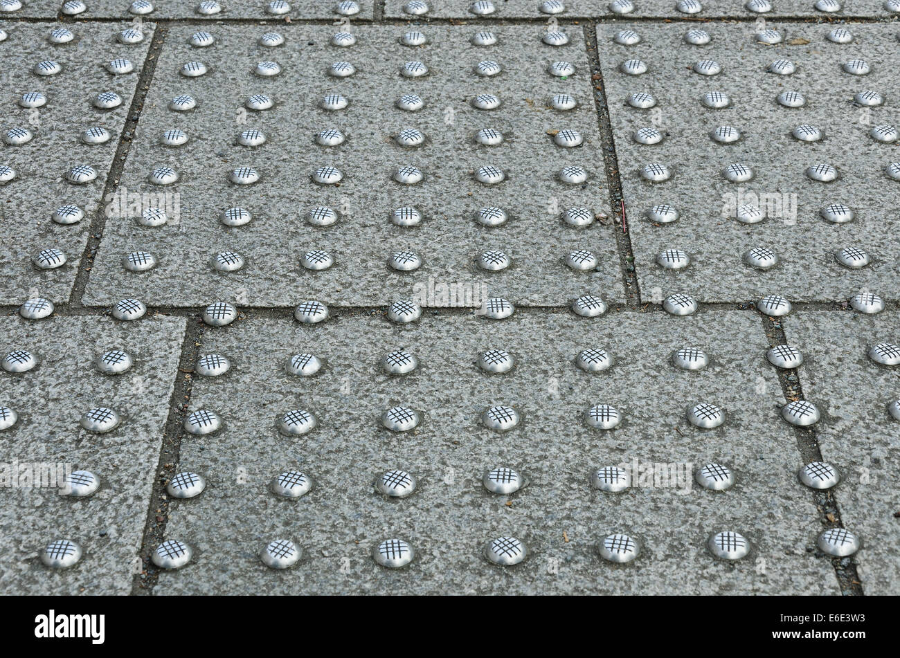 worn and bright stainless steel studs in natural gray paving flagstone ...