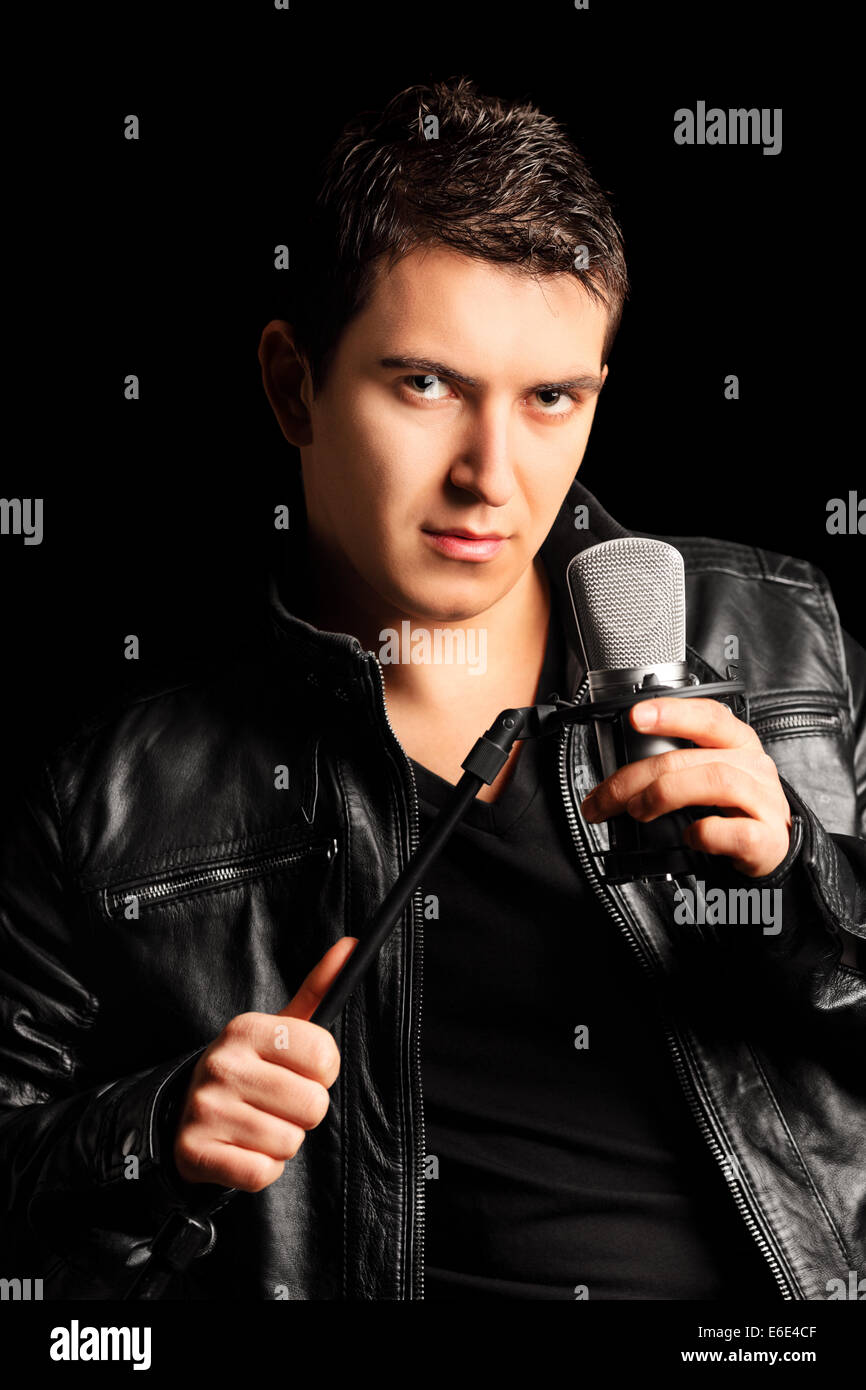 Male singer holding a microphone on black background Stock Photo - Alamy