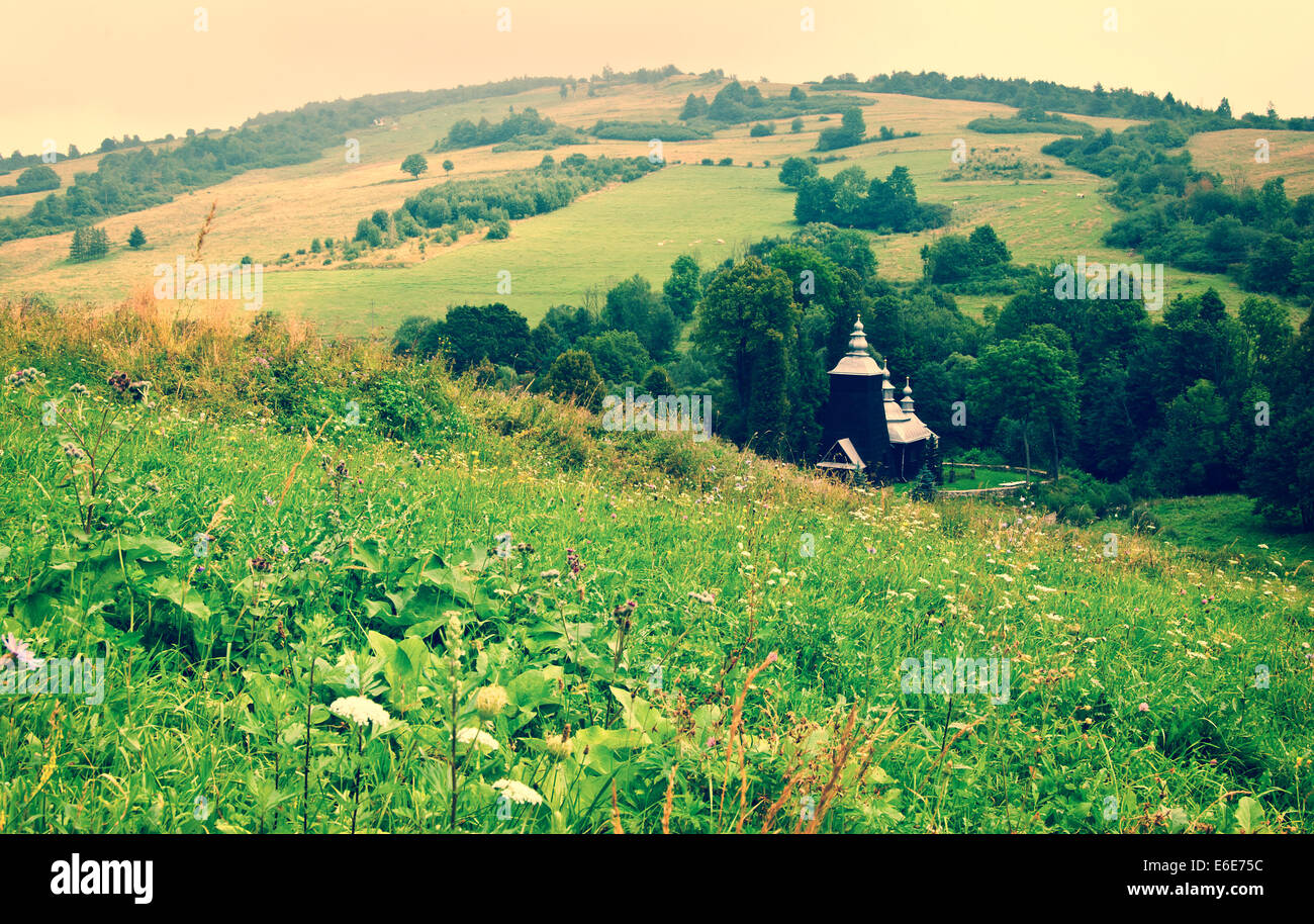Rural landscape in Poland with wooden church in Chyrowa. Vintage effect ...