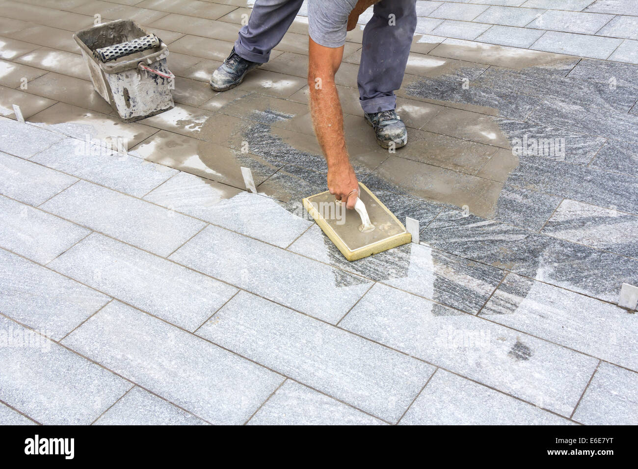 Worker grouting tiles with rubber trowel and gray cement mortar Stock ...