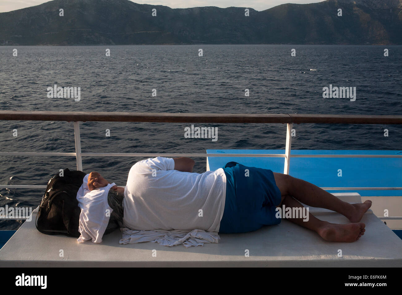 A man sleeps on the deck of a ship traveling to the port of Volos on ...