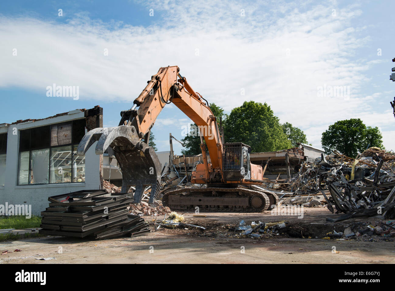 Excavator with grapple doing demolition work on office building in ...