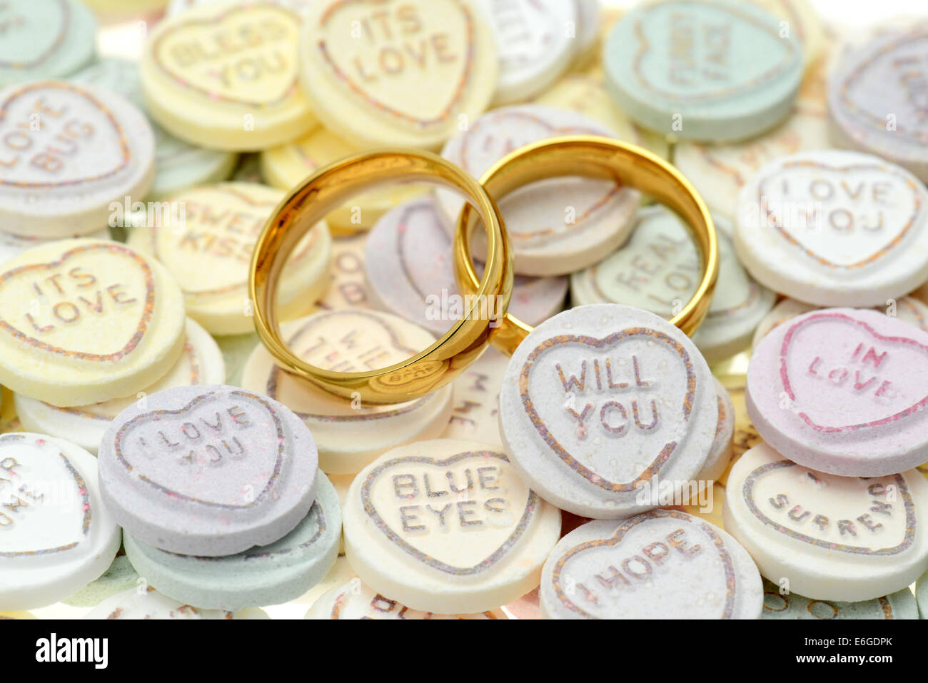 Two gold wedding rings on top of a pile of Loveheart candy sweets ...