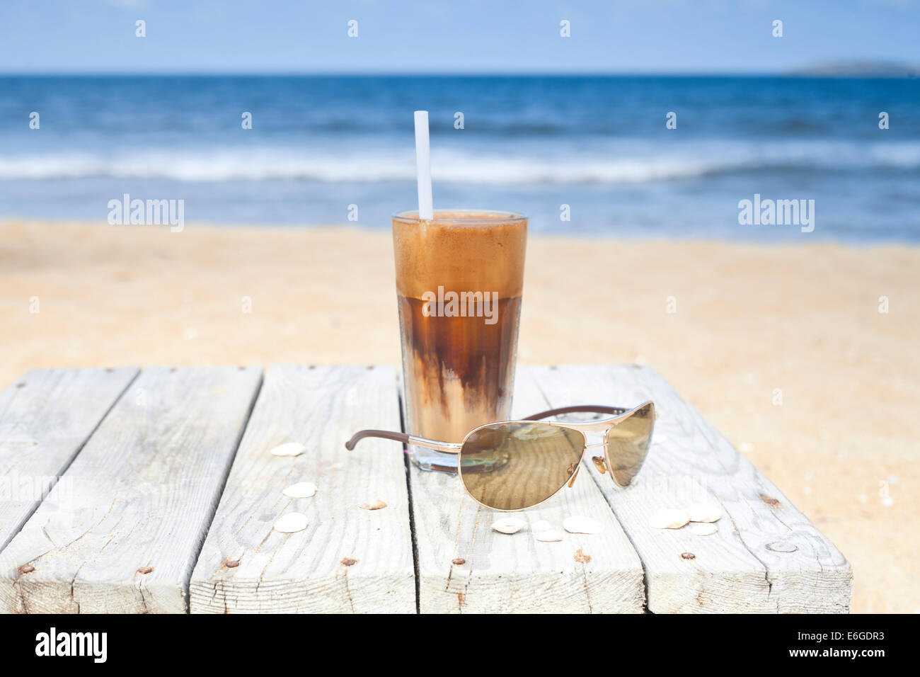 Iced coffee and glasses on a wooden table on the beach Stock Photo - Alamy