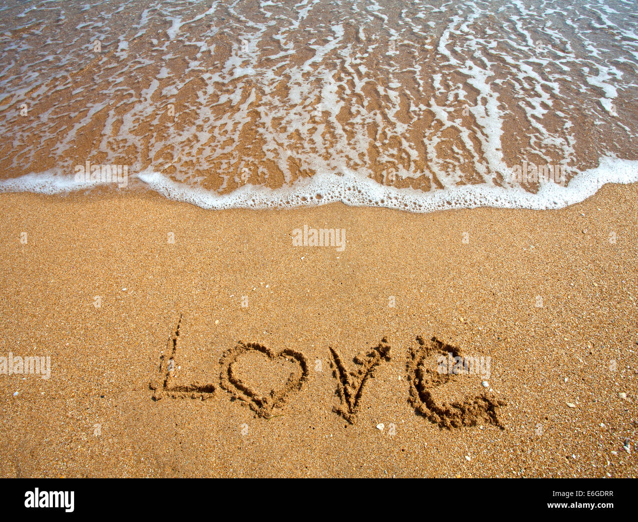 Love text drawn on the sand of a beach Stock Photo - Alamy