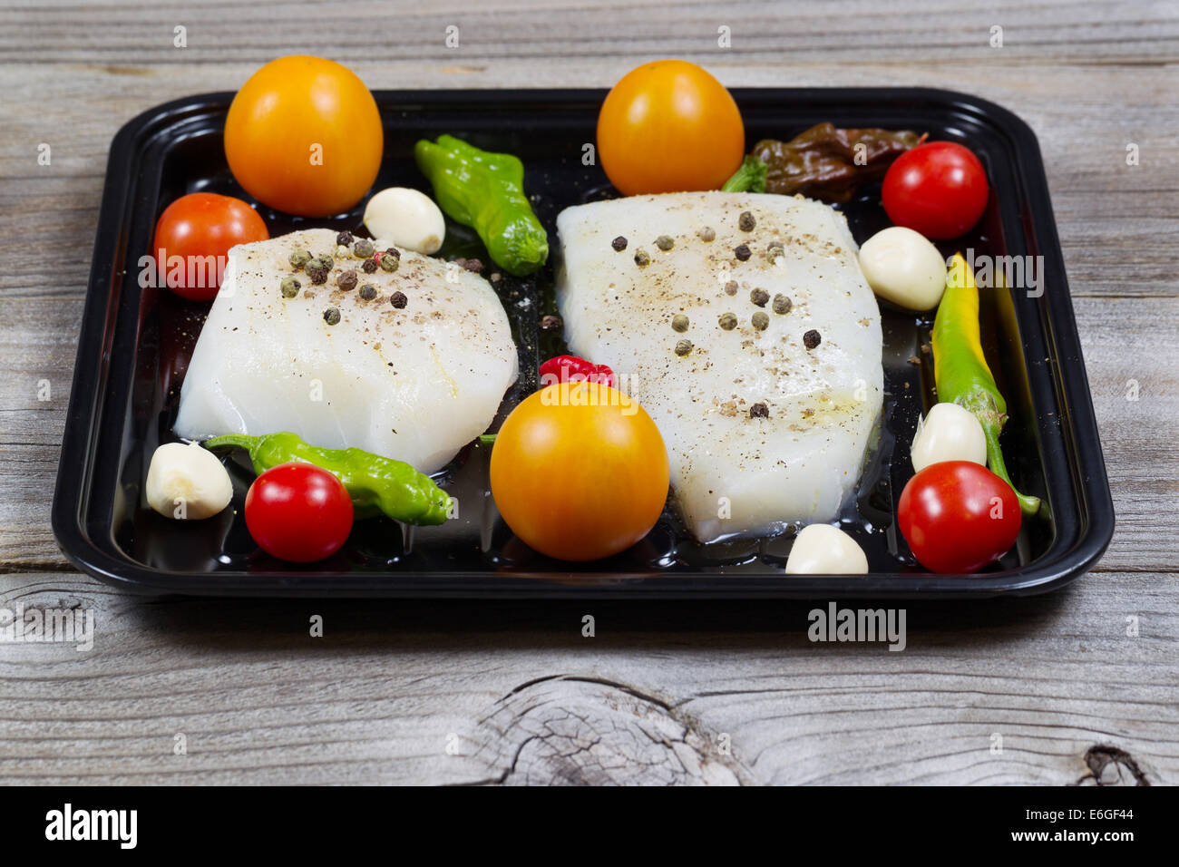 Front view of fresh raw Cod Fish Fillets in cooking pan with tomatoes ...