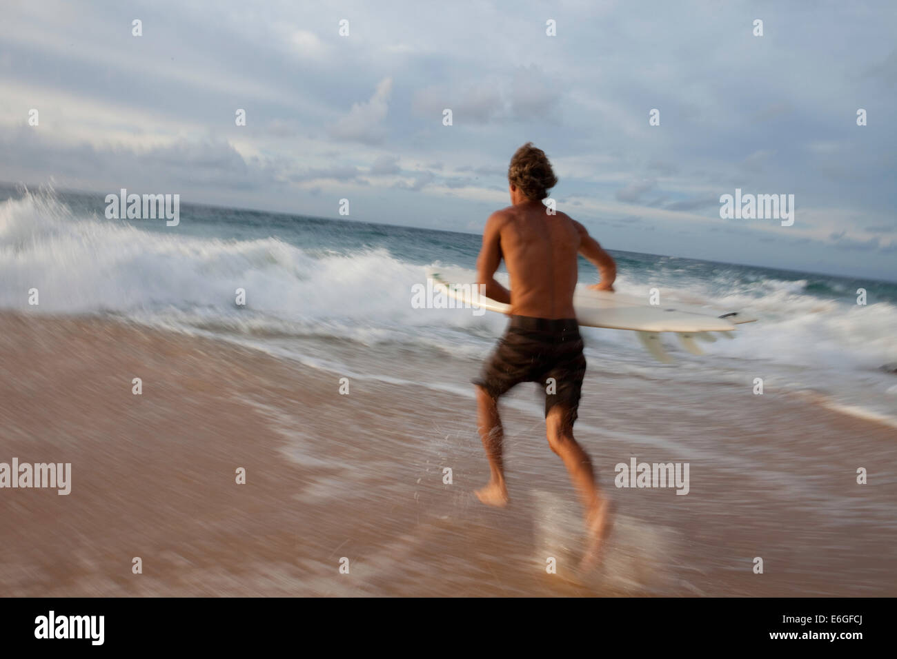 Surfer running into water at Sandy Beach Stock Photo - Alamy