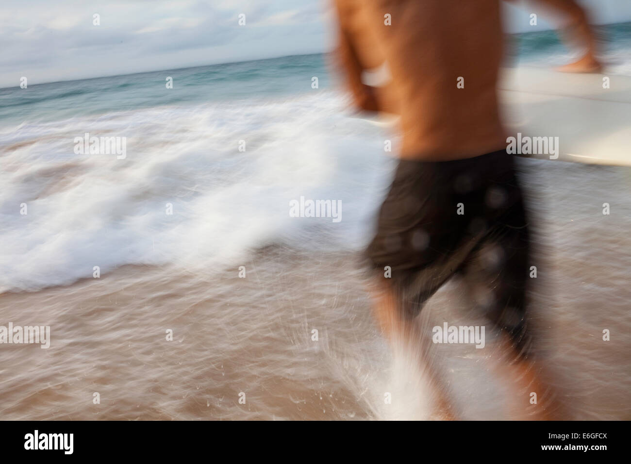 Surfer running into water at Sandy Beach Stock Photo - Alamy