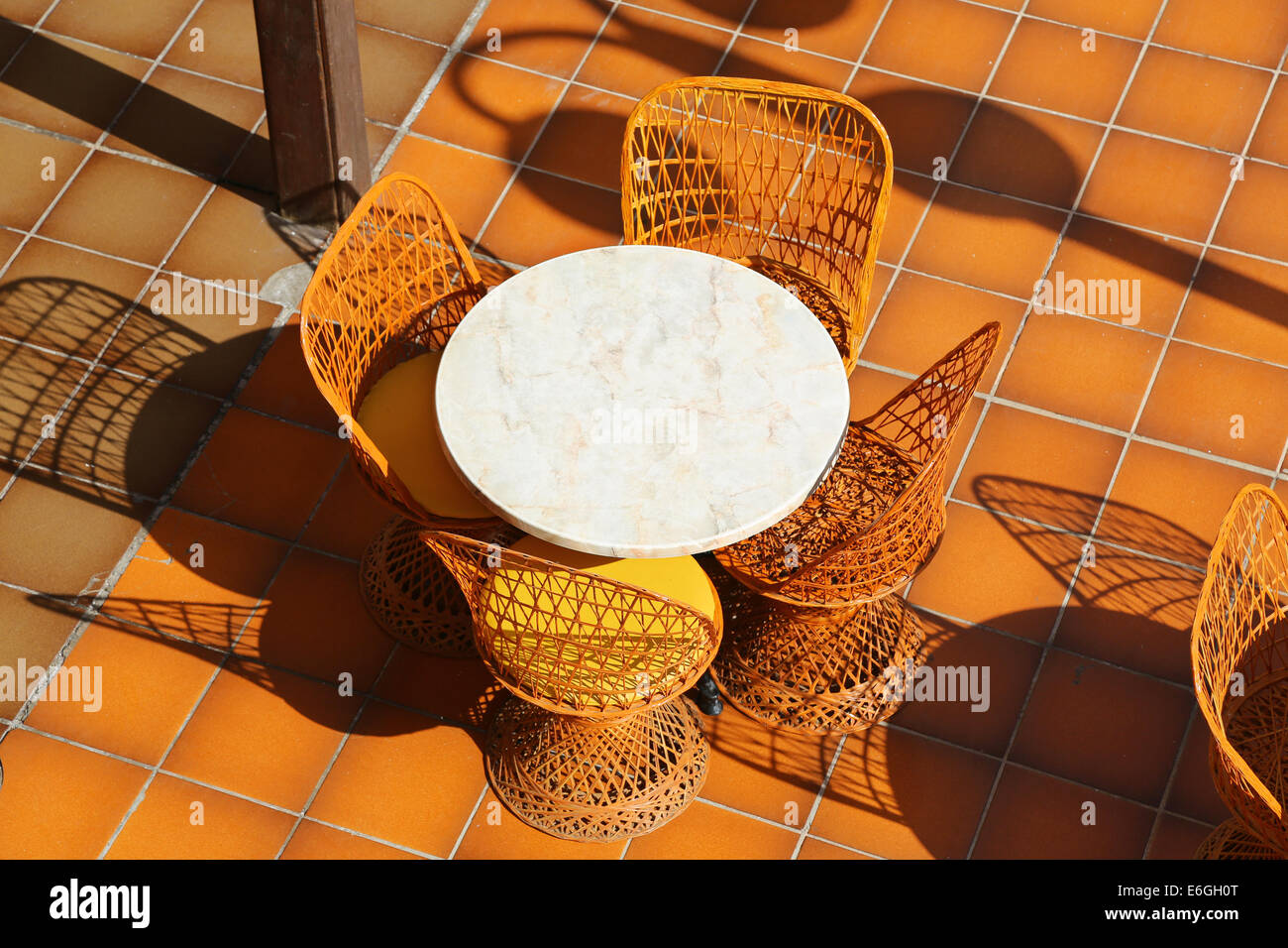 Round table and wicker chairs on tiled terrace Stock Photo - Alamy
