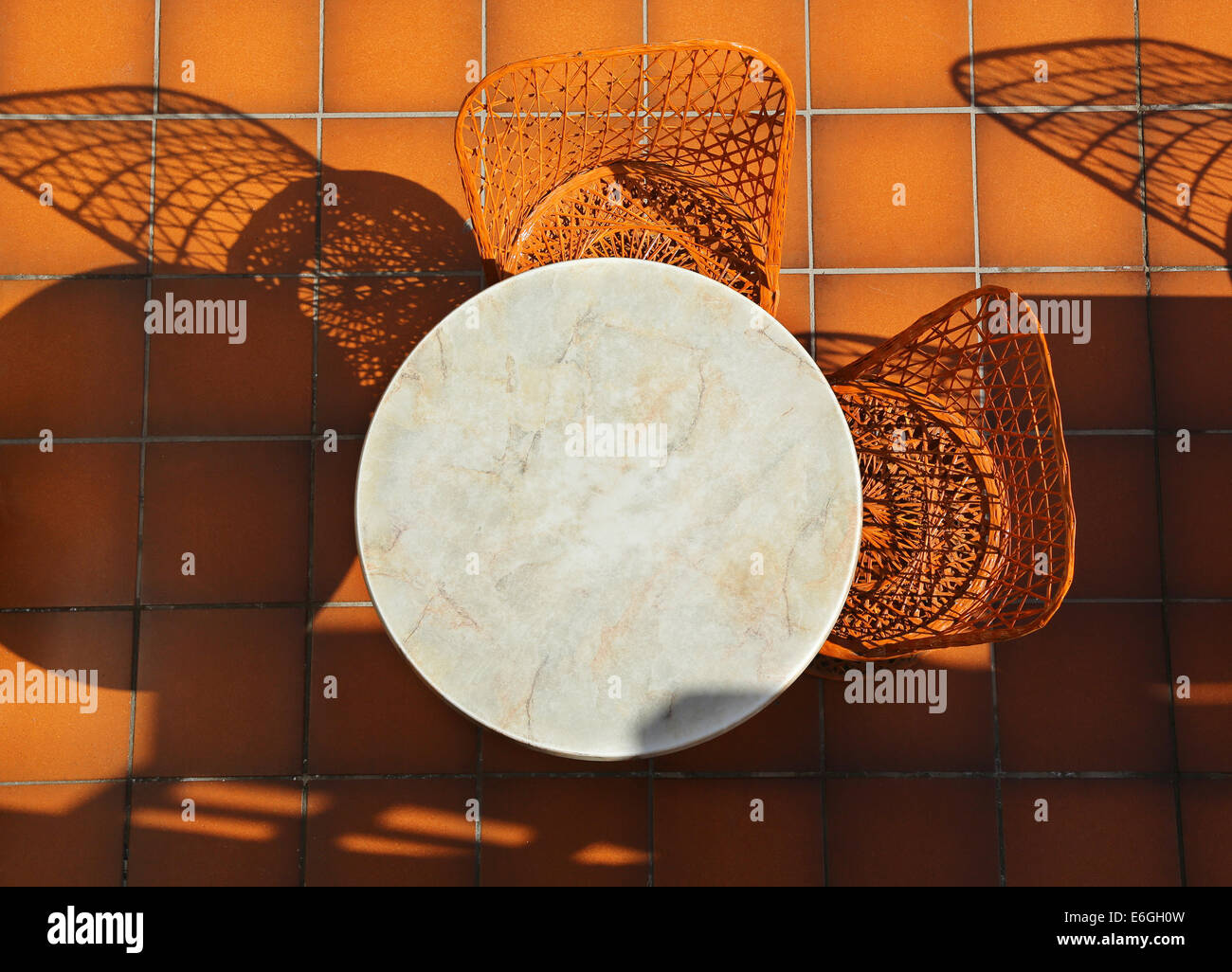 Round table and wicker chairs on tiled terrace Stock Photo - Alamy