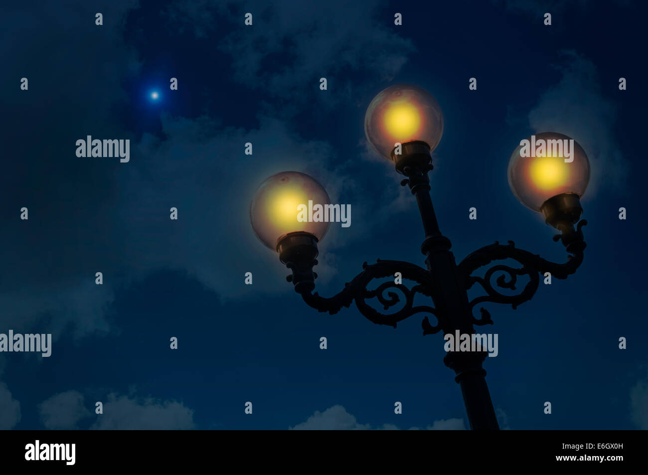 A lantern with three lamps illuminates a starry and cloudy night Stock ...