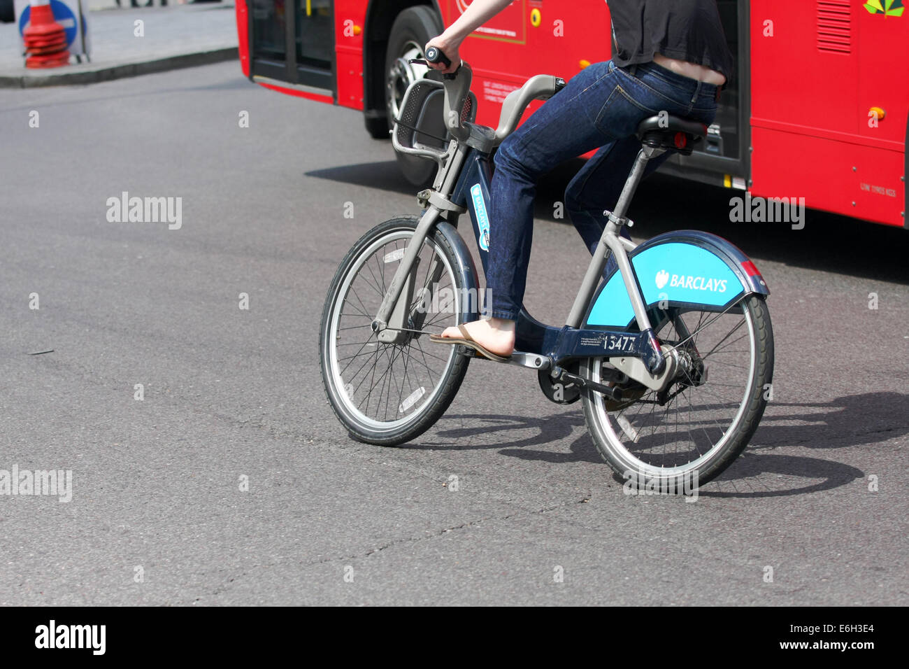 A cyclist riding a bicycle next to a red London bus in London Stock Photo - Alamy