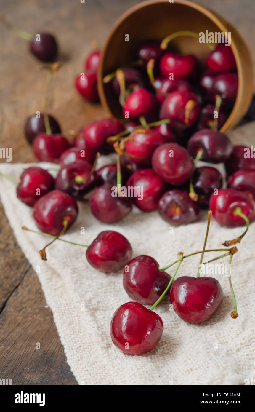 fresh s cherries spilling out from the bowl on wooden table background ...