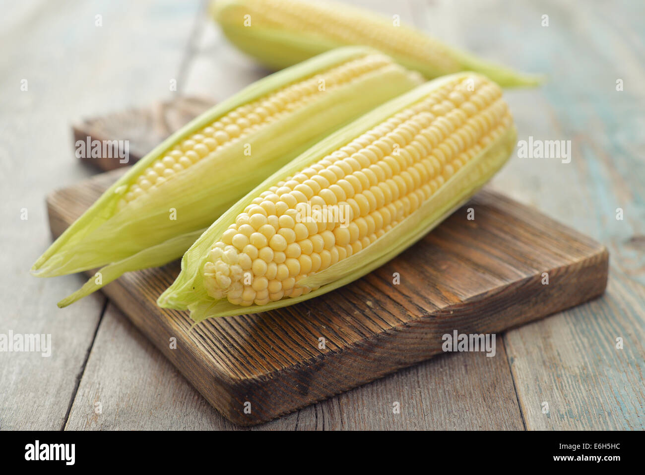 Raw corn cobs on wooden background closeup Stock Photo - Alamy