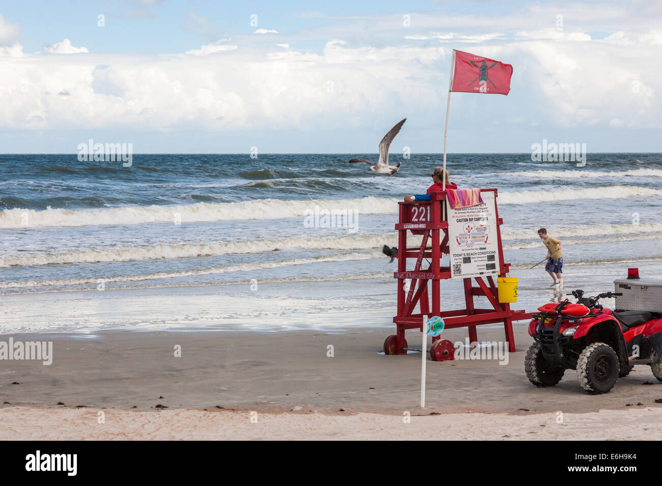 Lifeguard watches over young boy playing with skim board in the surf at ...
