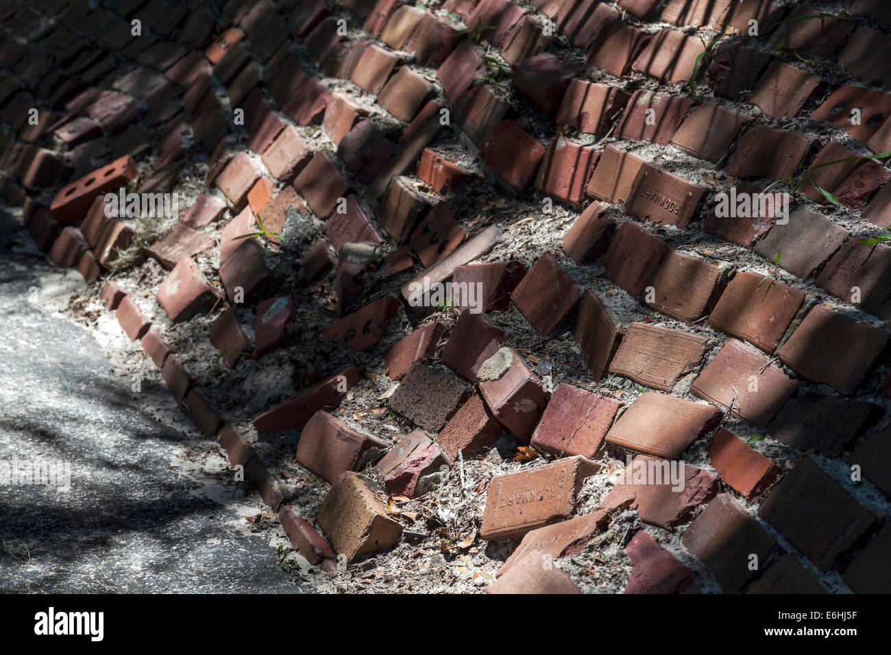 Old bricks of riprap-style revetment along a hilly driveway protect a ...