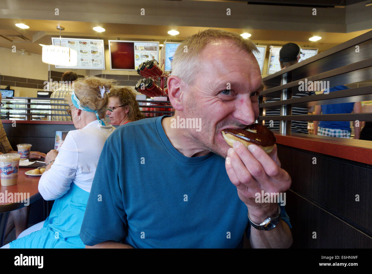 A man eating a doughnut in A Canadian Tim Hortons Restaurant Stock ...