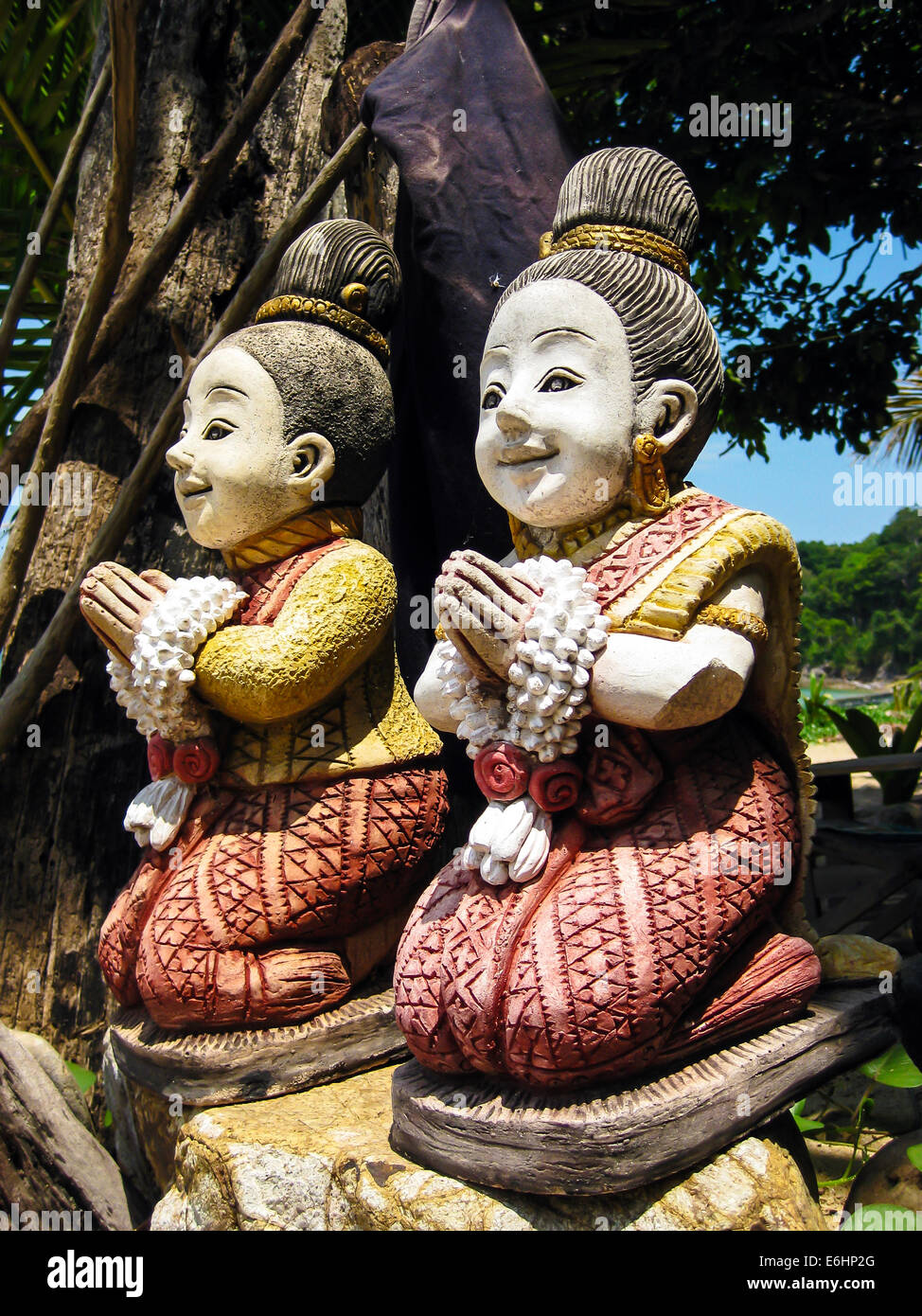 Two colored statues of kneeling praying women in Thailand Stock Photo ...