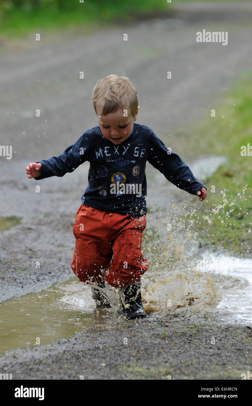 A young boy getting soaked running through a puddle Stock Photo - Alamy
