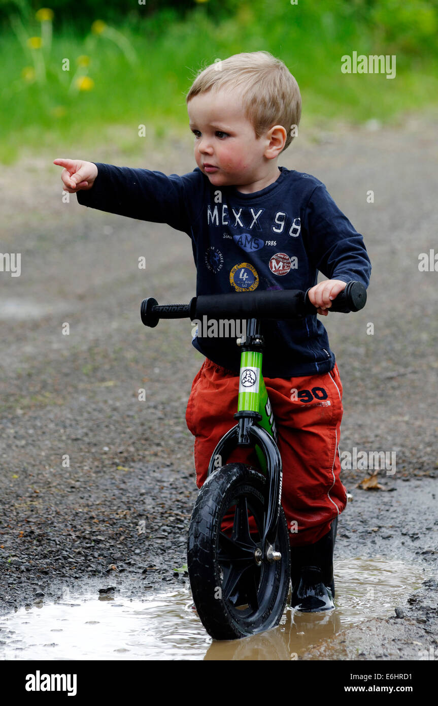 A young boy riding a balance bike through a puddle Stock Photo - Alamy