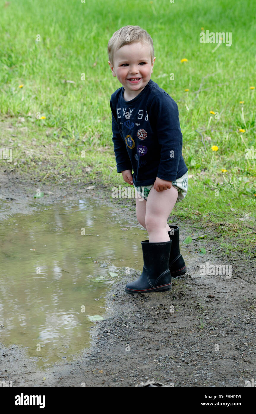 A young boy getting soaked running through a puddle Stock Photo - Alamy
