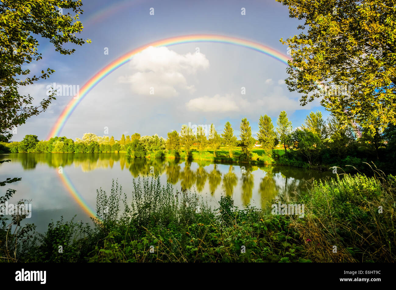 Bright rainbow reflected in a fishing lake Stock Photo - Alamy