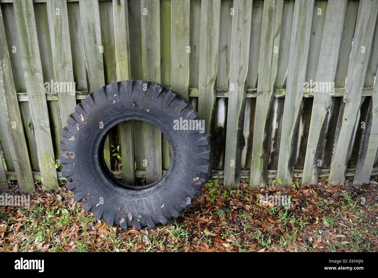 Backyard tire against a tired fence Stock Photo - Alamy