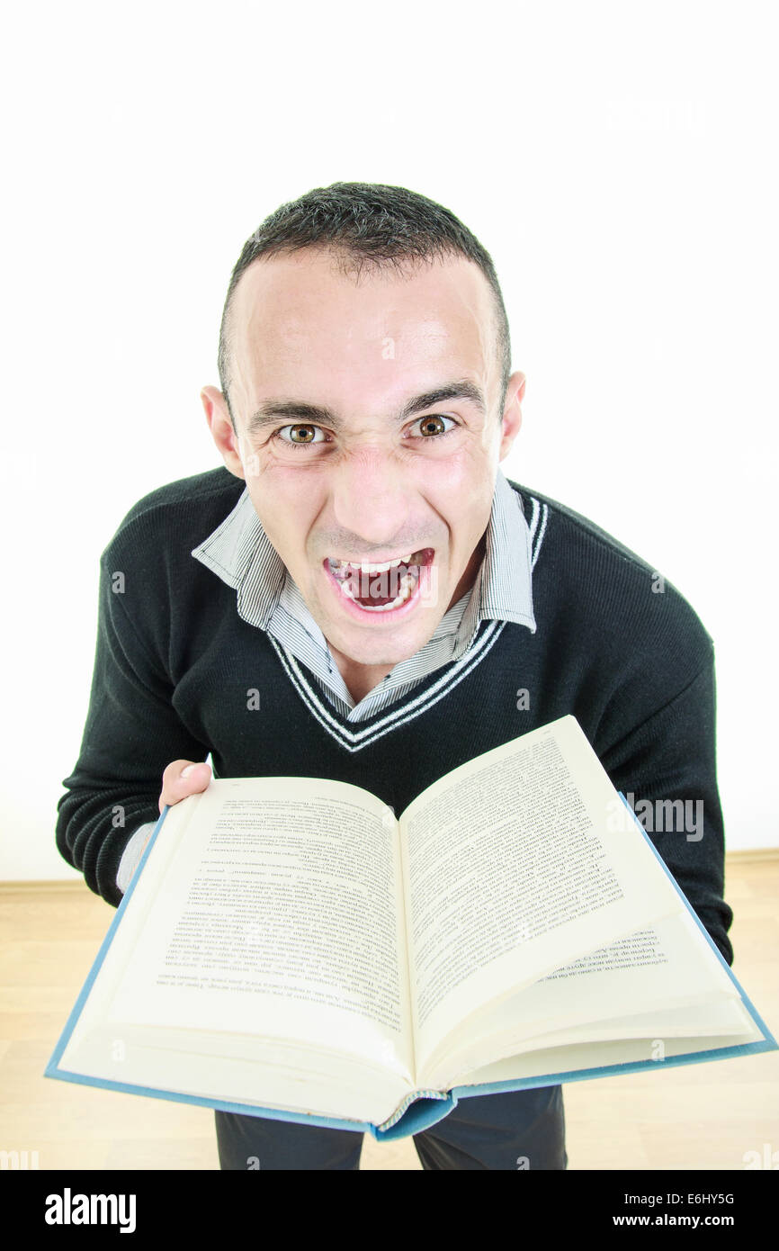 Angry young man holding a book tired of reading and studying with face ...