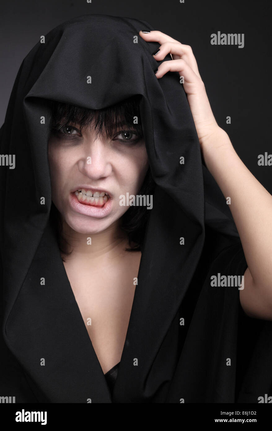 Scary woman with a pale face. Covered with black cloth Stock Photo - Alamy