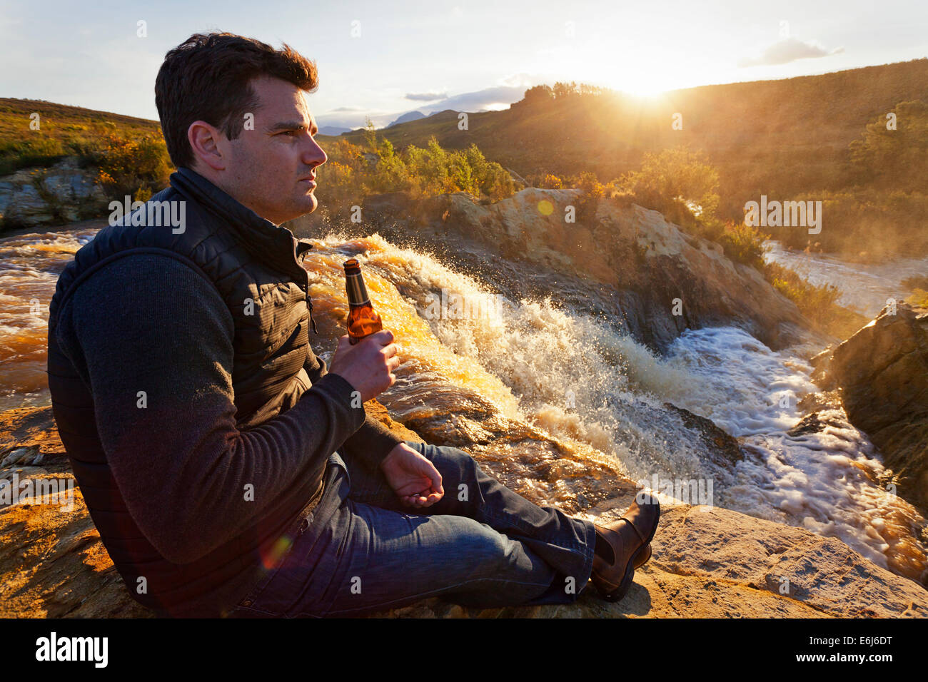 Man enjoying a beer next to a waterfall Stock Photo - Alamy