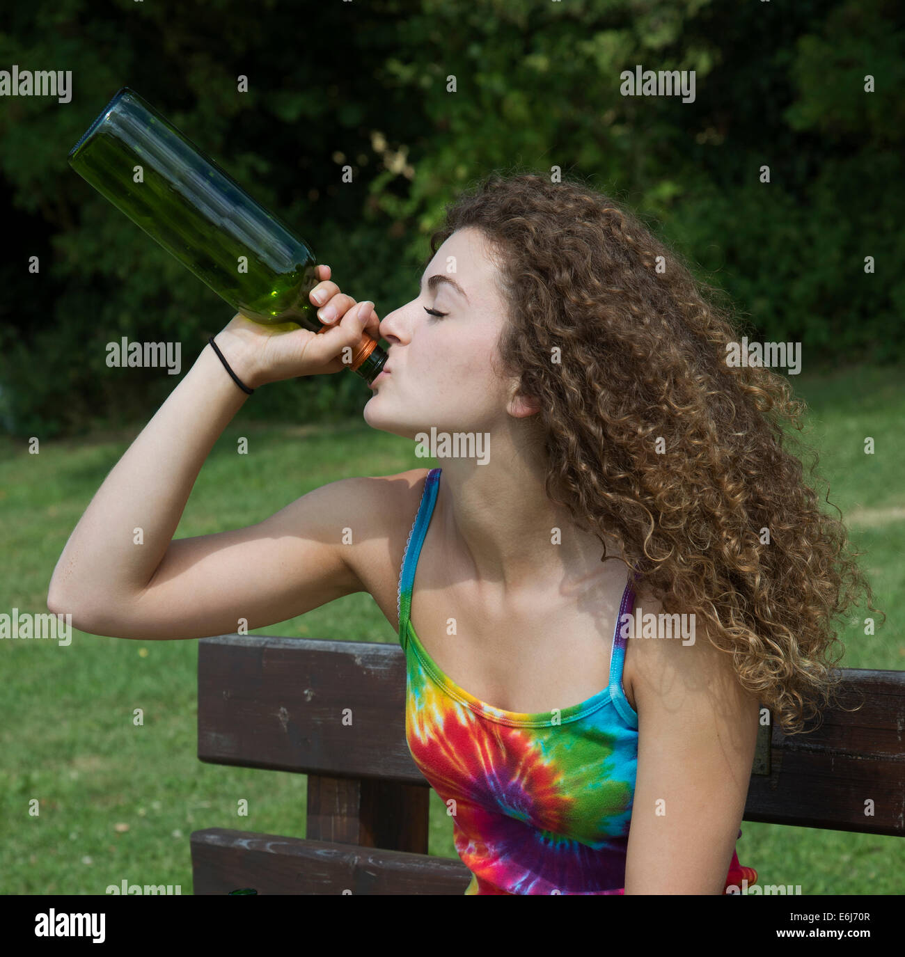Teenage girl drinking alcohol on a park bench Stock Photo - Alamy