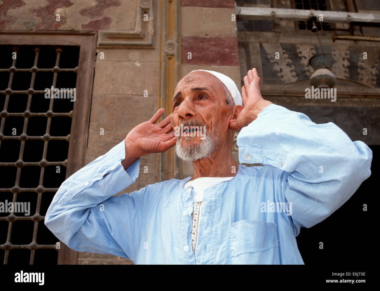 An elderly imam makes the prayer call or adhan from a Cairo mosque ...
