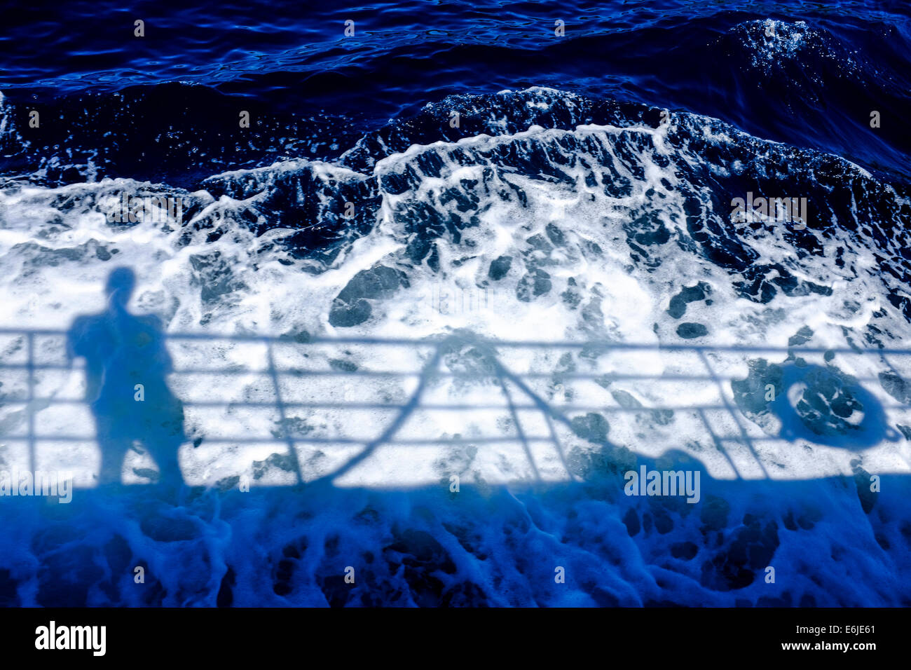shadow of man and the railings from a ship cast on the white water of ...