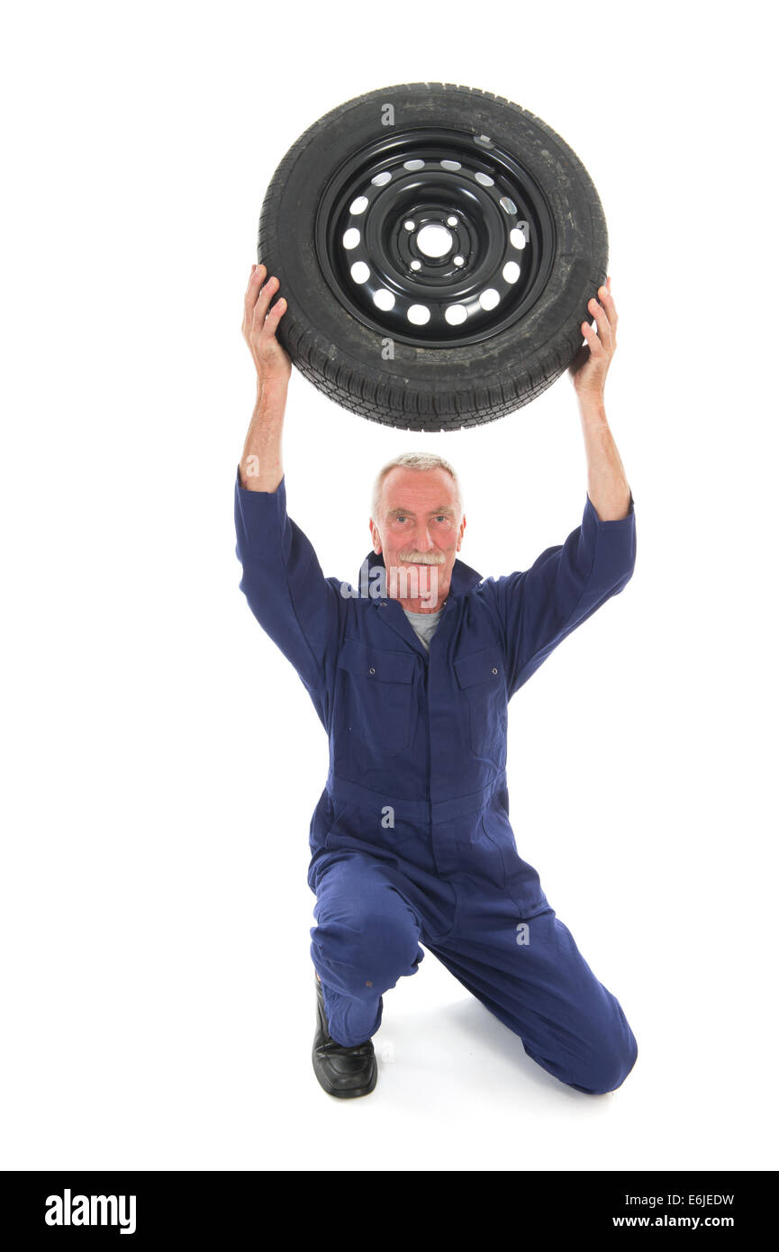 Mechanic lifting a wheel in blue overall isolated over white background ...