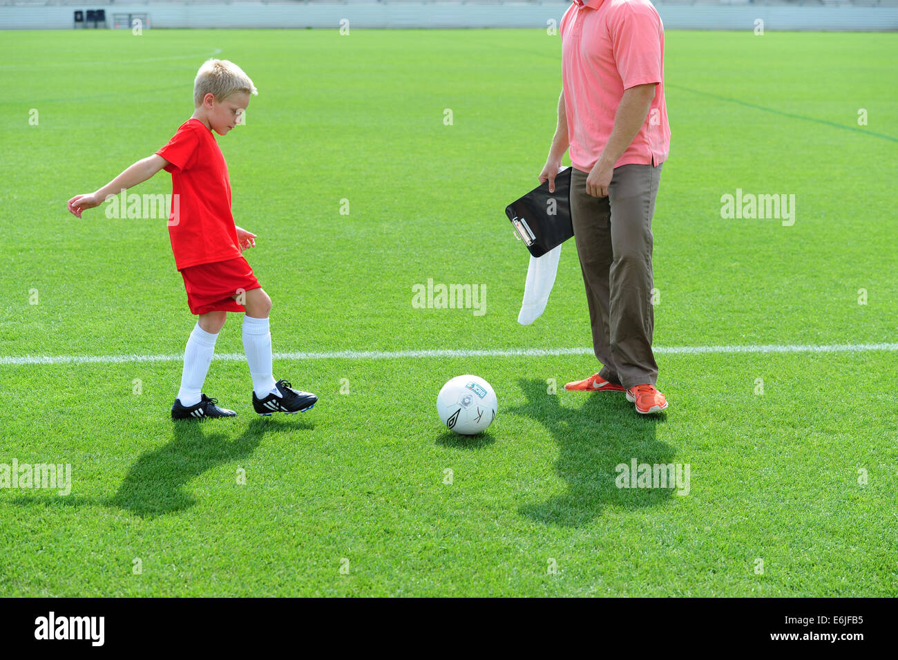 Boy 9 10 11 playing football futbol soccer on grassy pitch field ...