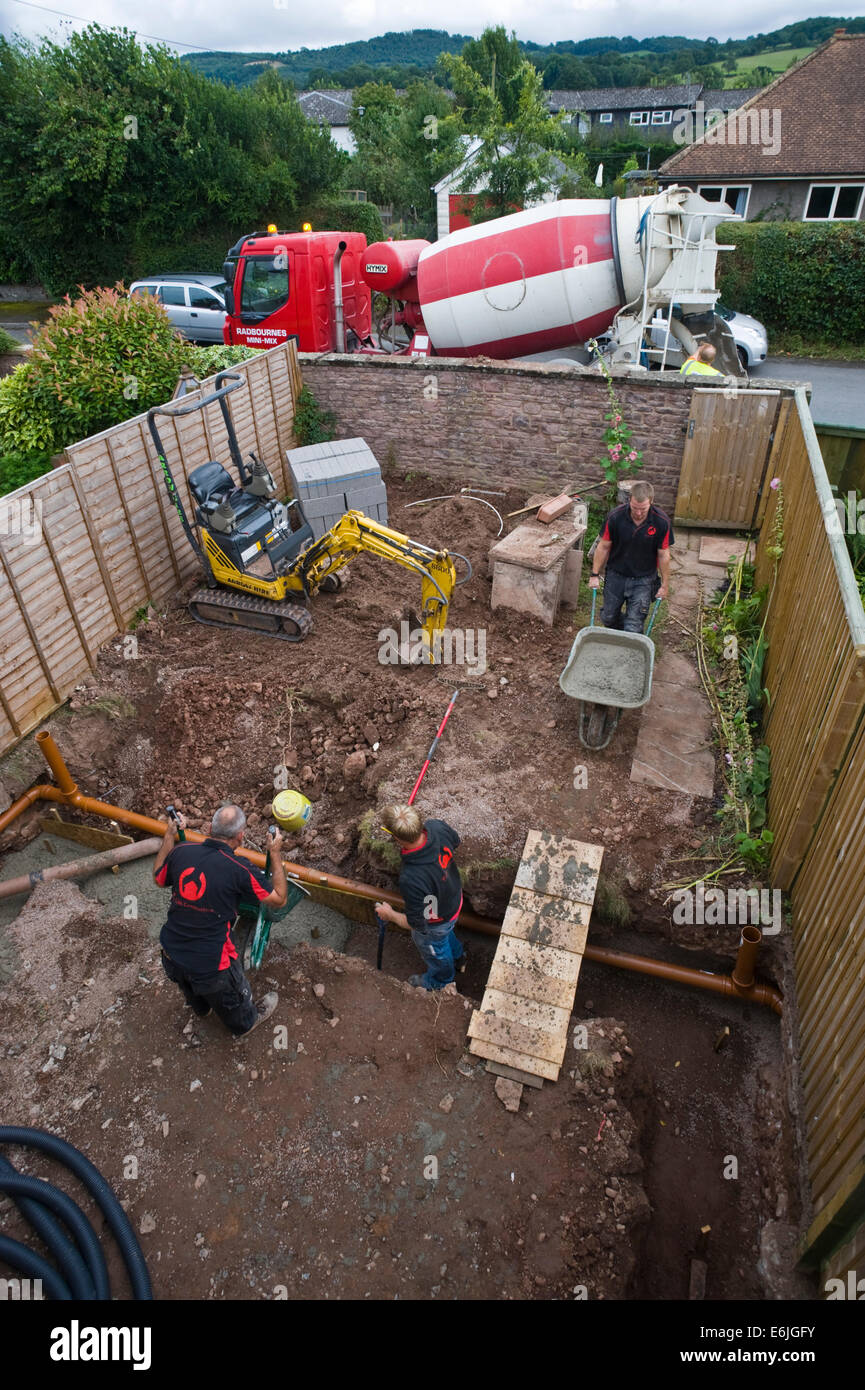 Builders pouring concrete into foundations of house extension at Hay-on ...