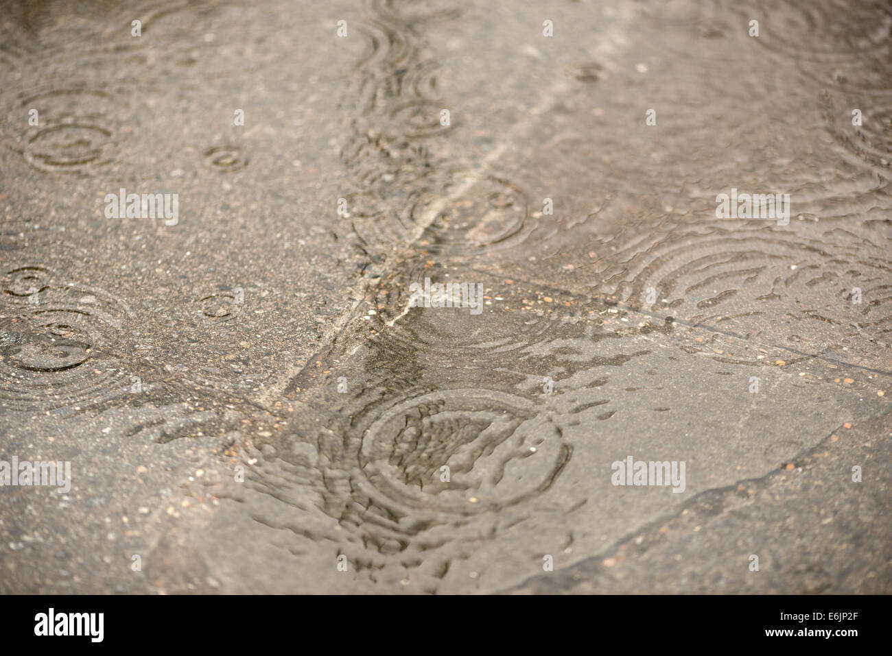 raindrops causing ripples patterns in puddle over flagstone pavement on ...