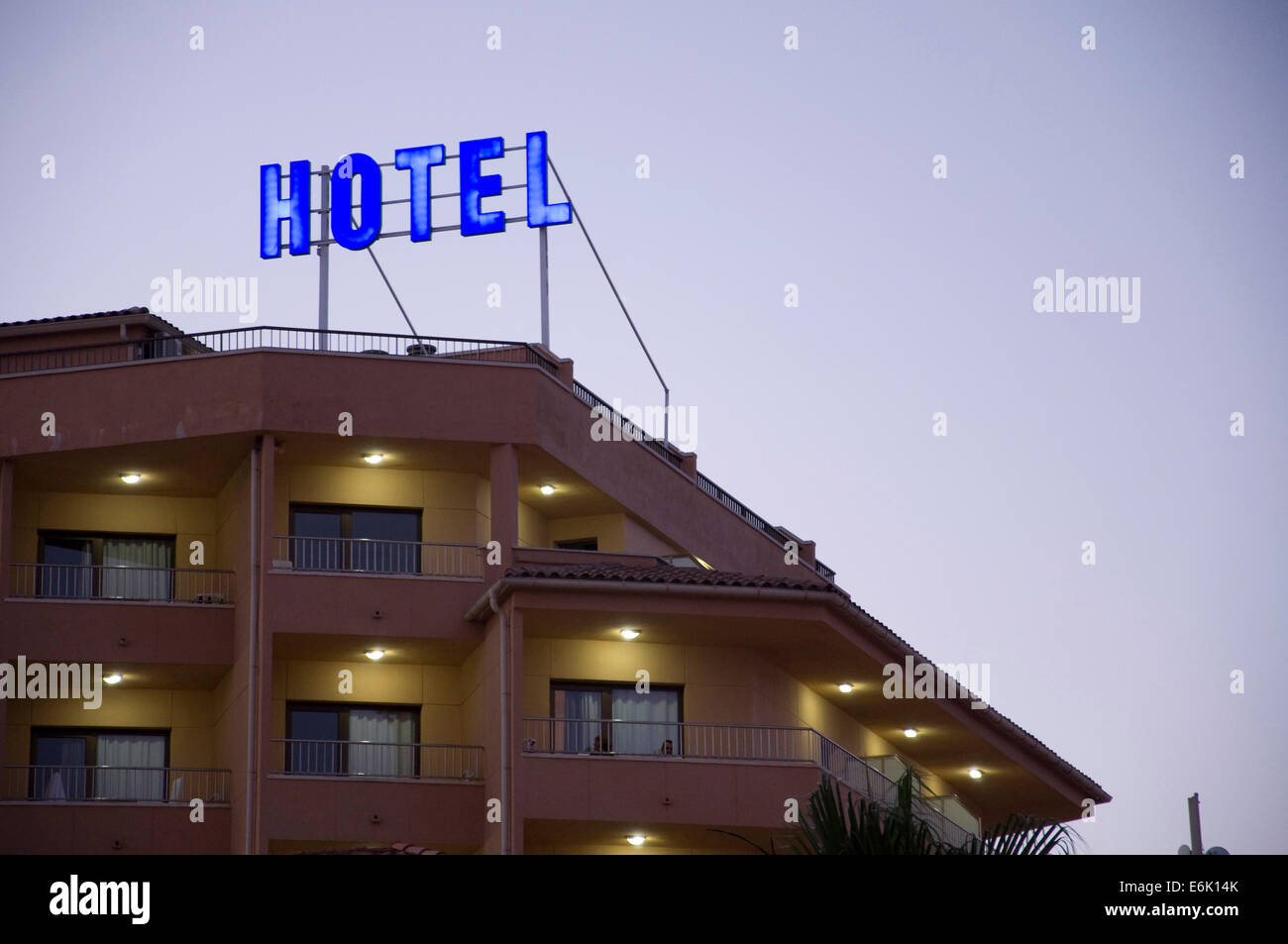 Illuminated in blue Hotel sign at sunset Stock Photo - Alamy