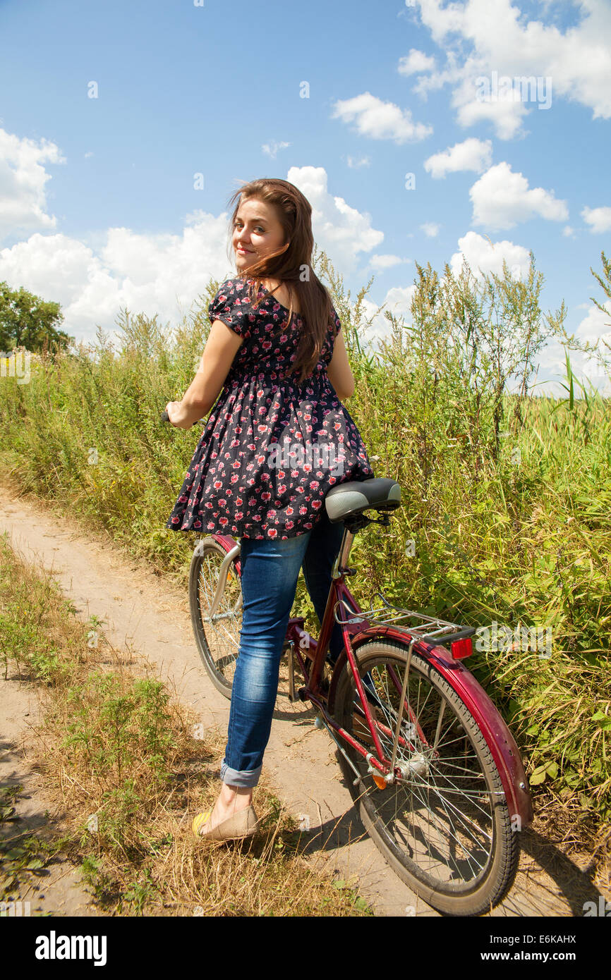 Smiling girl riding her bike in the field in summertime Stock Photo - Alamy