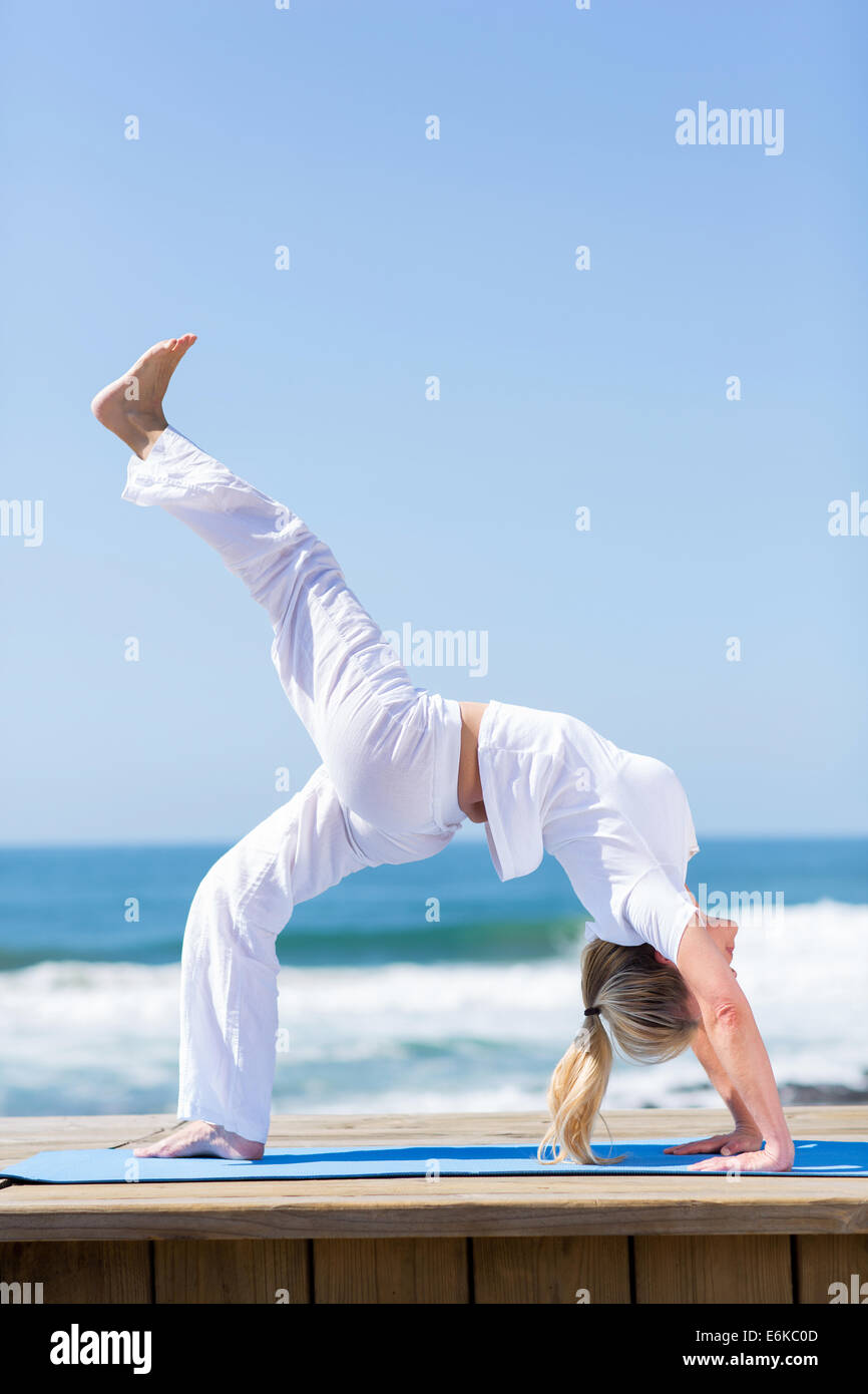 flexible mature woman practicing yoga by the beach Stock Photo - Alamy